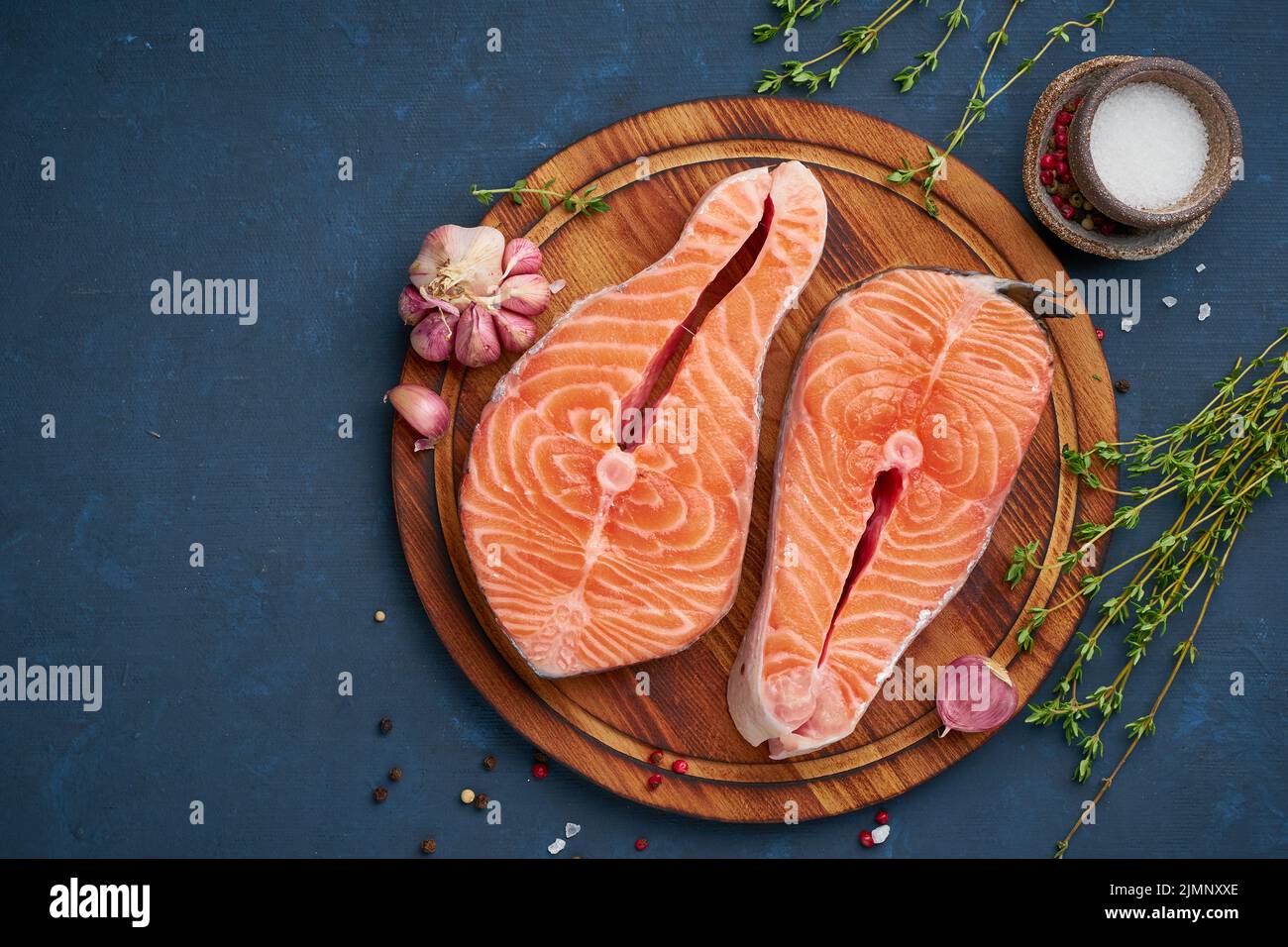 Two salmon steaks, fish fillet, large sliced portions on chopping board ...
