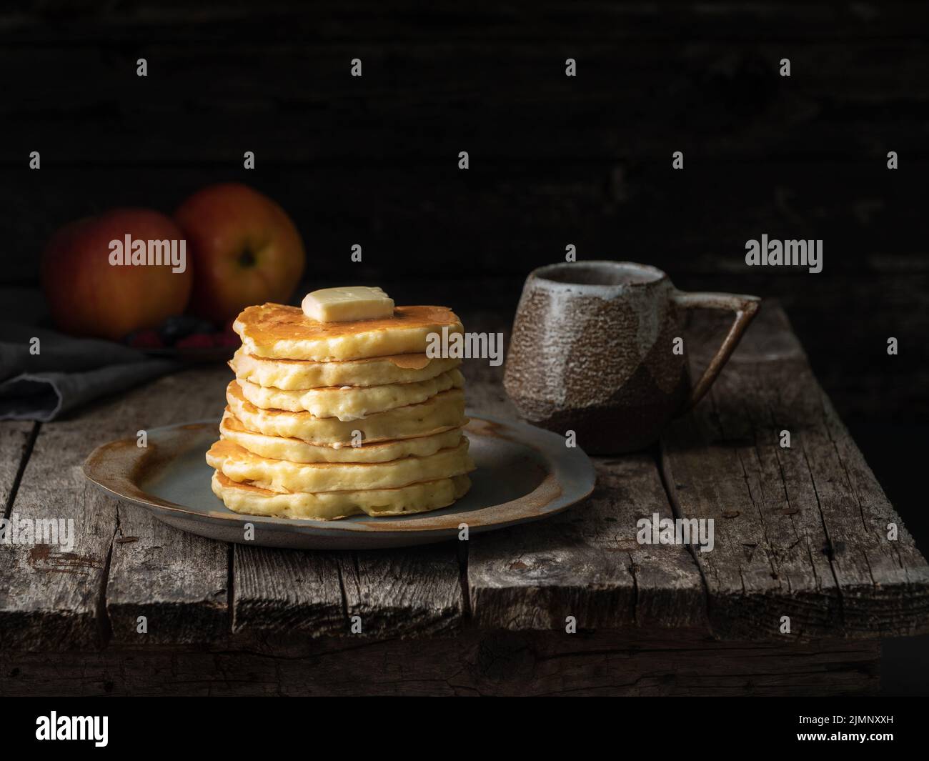 Pancake with butter and cup of tea. Dark moody old rustic wooden ...