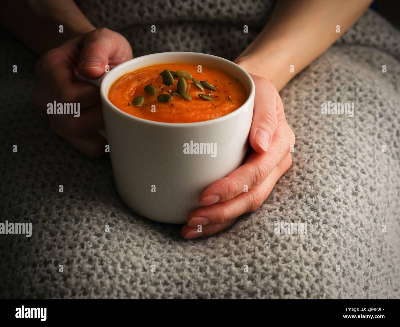Pupmkin cream soup in hands, dietary vegetarian lunch. Side view. Dark ...