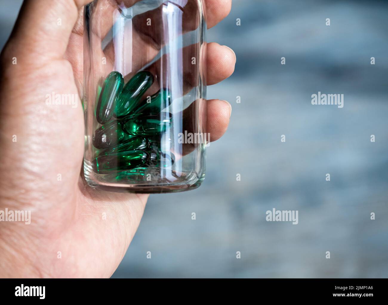 Close up green vitamins or supplements in the small clear glass bottle ...