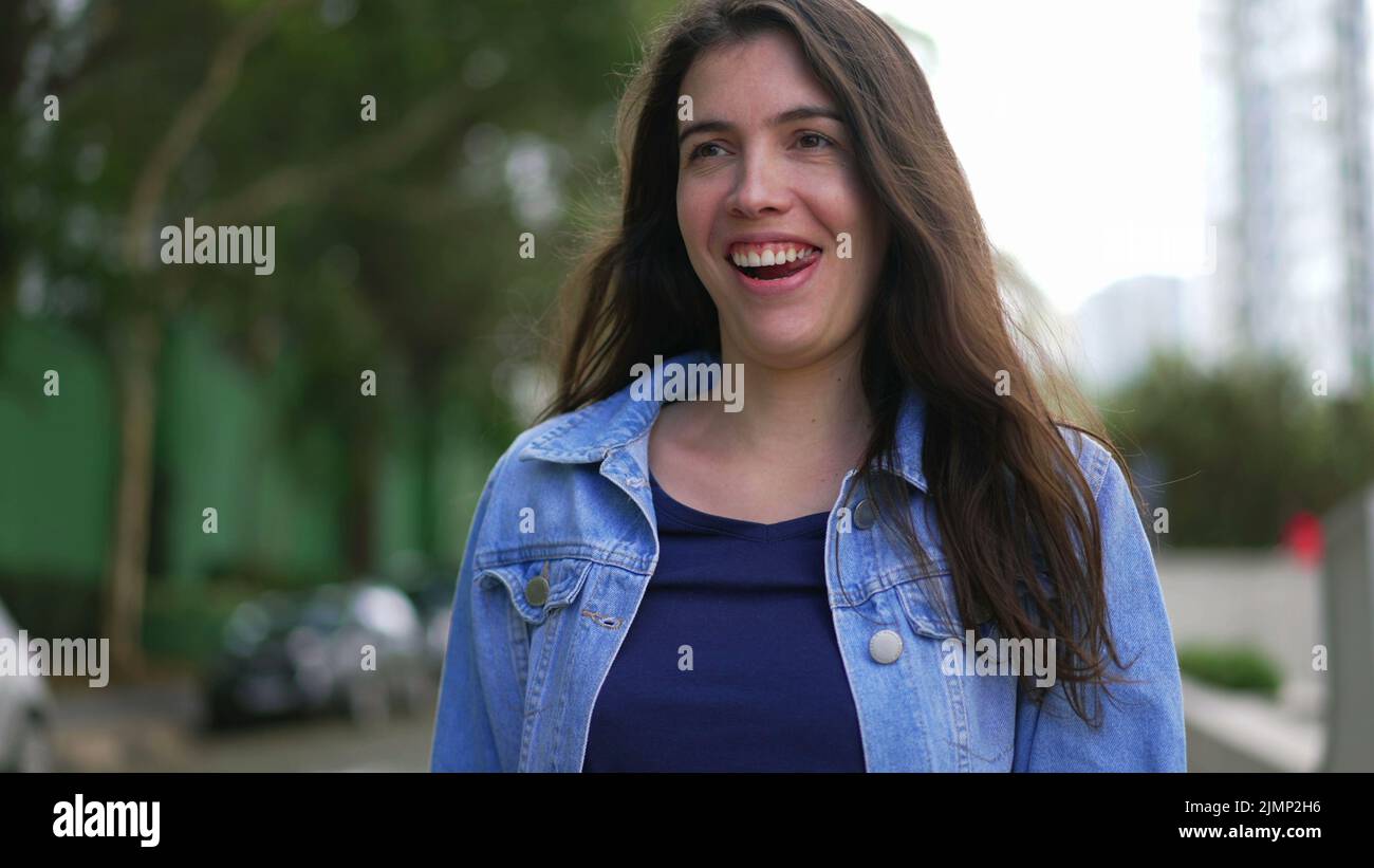Happy young woman walking outside. A joyful expressive girl smiling ...