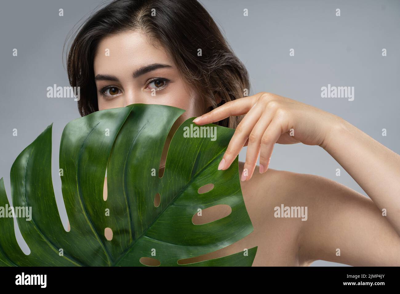 Beautiful woman with a smooth skin holding green tropical leaf on white ...