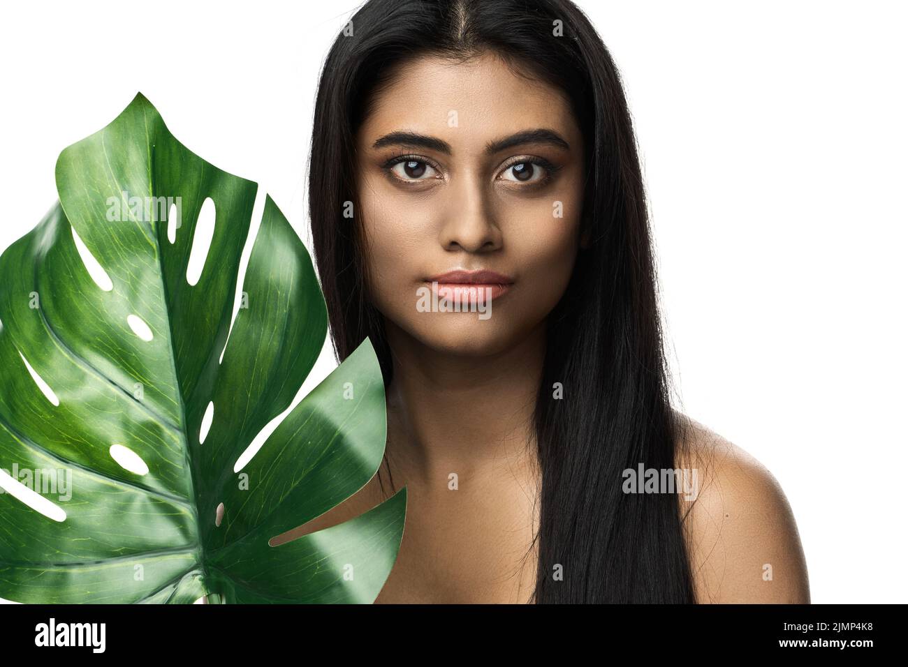 Beautiful Indian woman with a smooth skin holding green tropical leaf ...