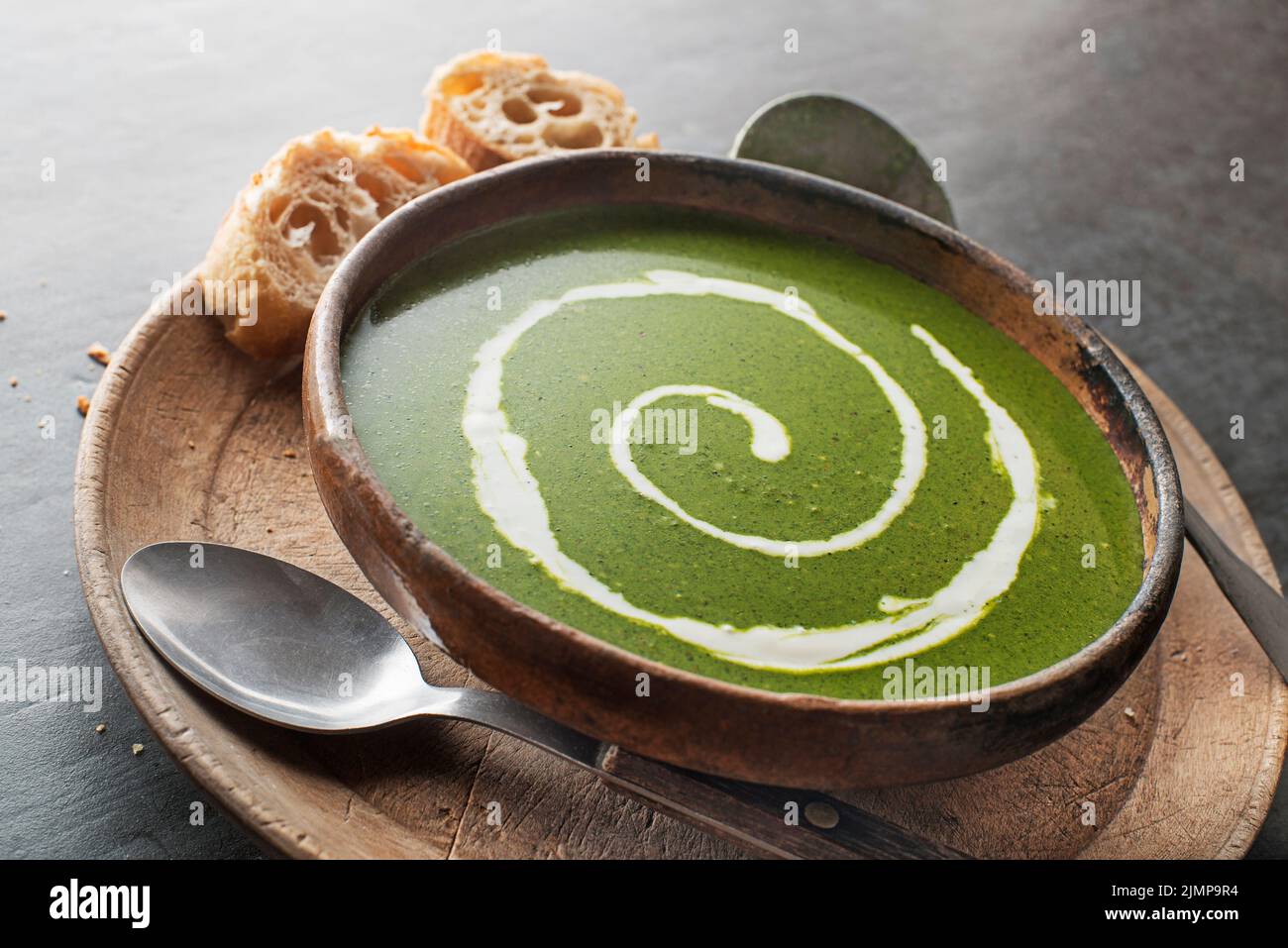 Fresh vegetable creamy soup with cream and on grey background close up ...