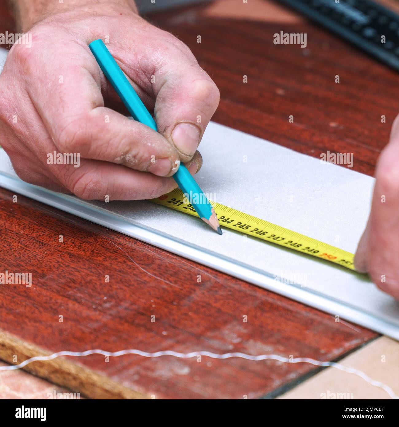The worker marks the plastic panel with a pencil and tape measure or ...