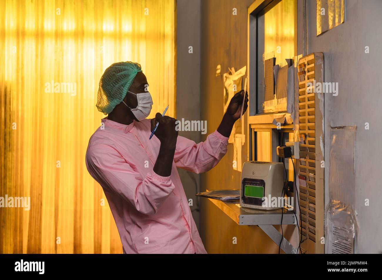 African quality control employee man in sterile suit clock in with time ...