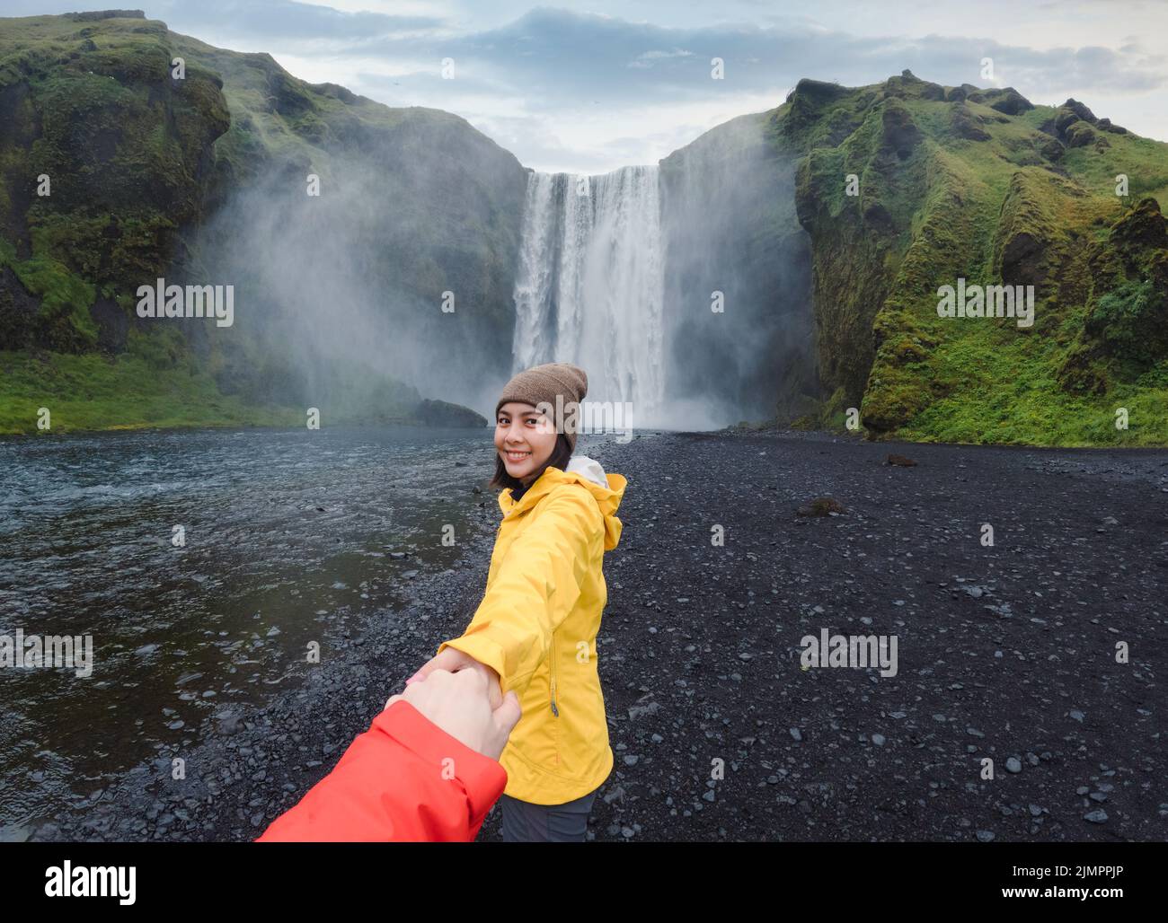Asian woman in yellow jacket holding hands with couple at front of ...