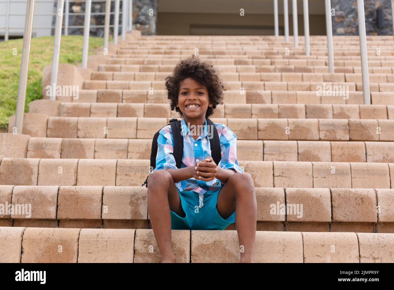 Portrait of smiling african american elementary schoolboy sitting on ...
