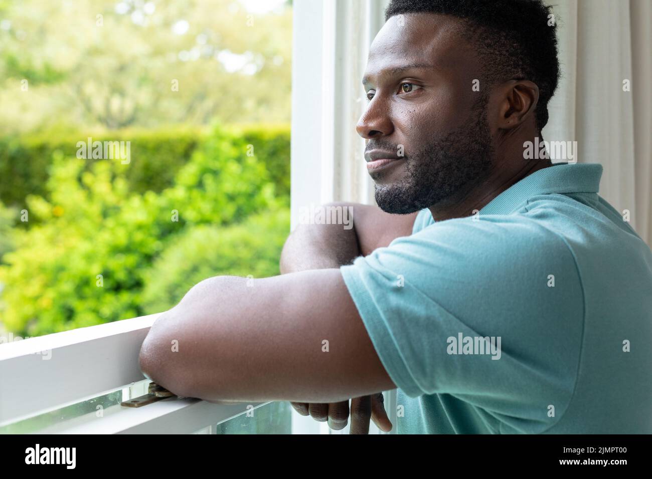 Thoughtful afrcian american young man at home looking through window ... Thoughtful afrcian american young man at home looking through window ...