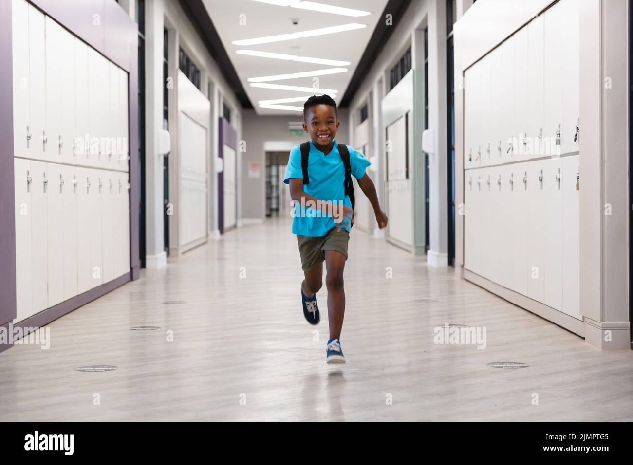 Full length of smiling african american elementary schoolboy running in ...