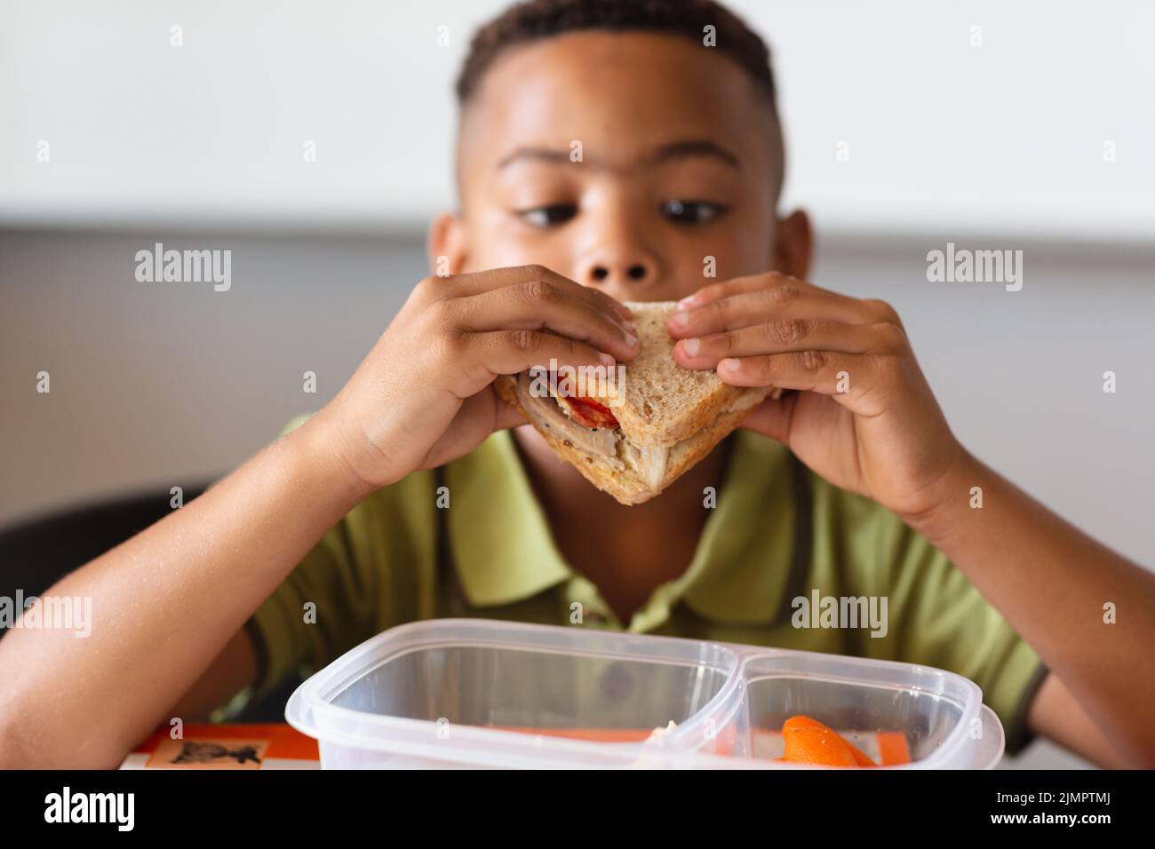 Close-up of african american elementary schoolboy eating sandwich ...