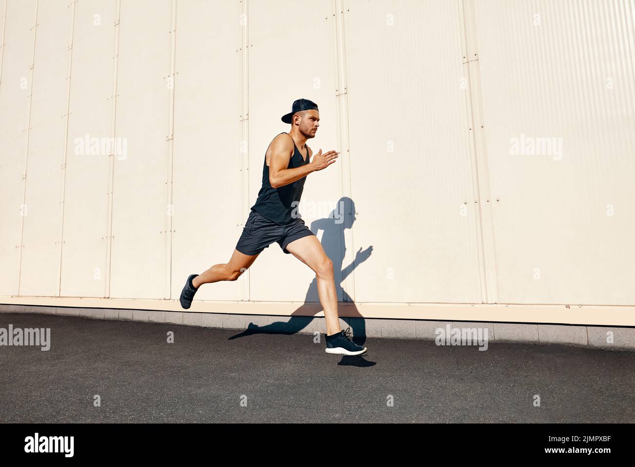 Young man runner running along wall with copy space Stock Photo - Alamy