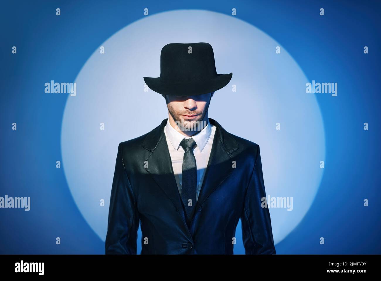 Portrait of handsome man in black coat hiding face behind his hat in ...