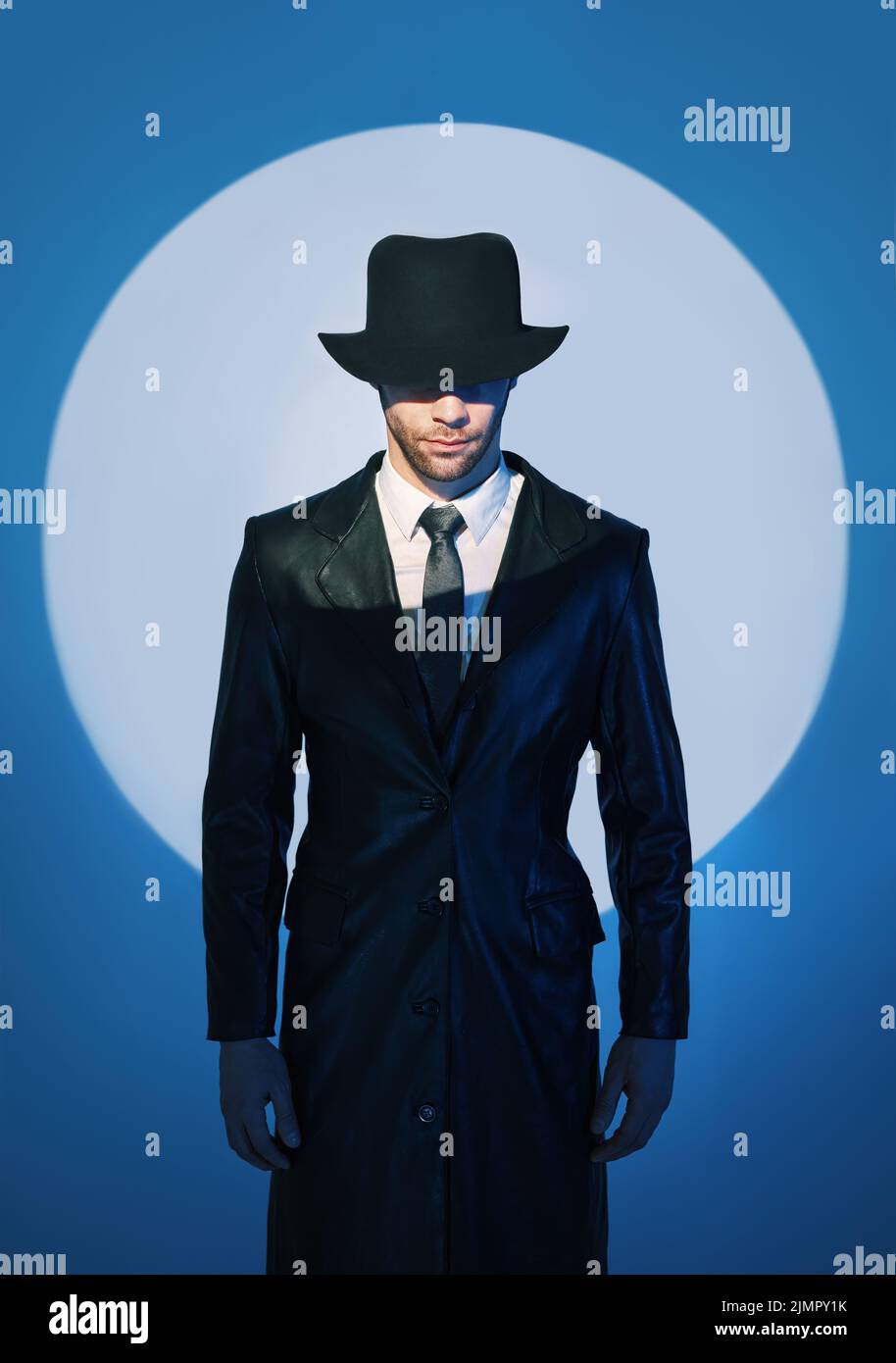 Portrait of handsome man in black coat hiding face behind his hat in ...