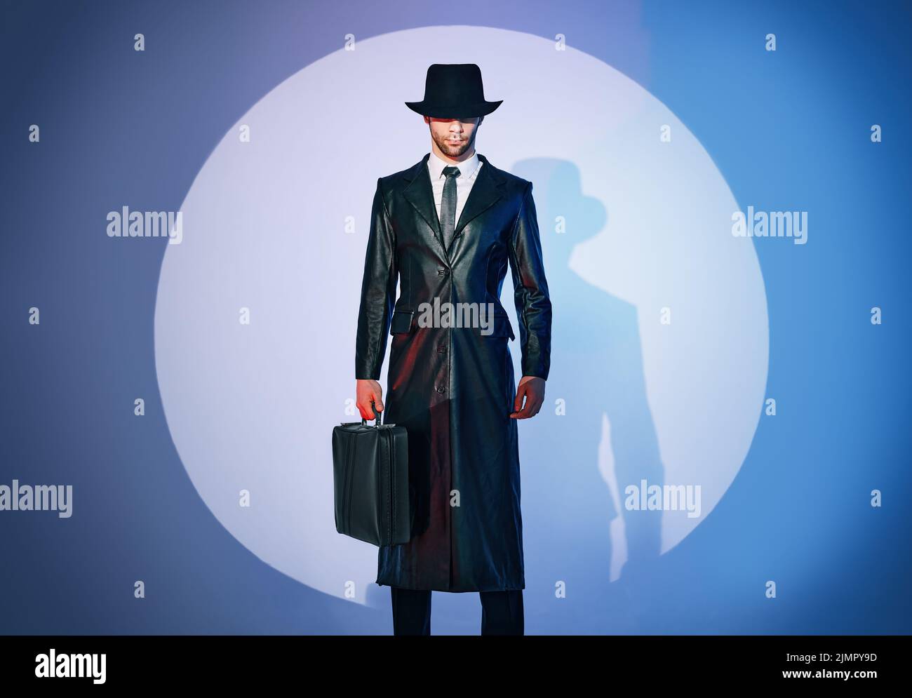 Full length portrait of handsome man in black coat and hat holding ...