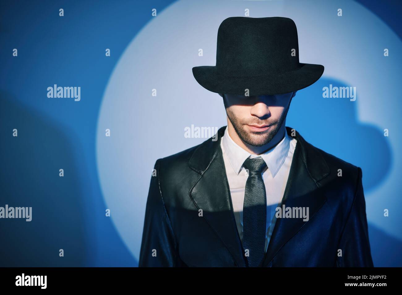 Portrait of handsome man in black coat hiding face behind his hat in ...
