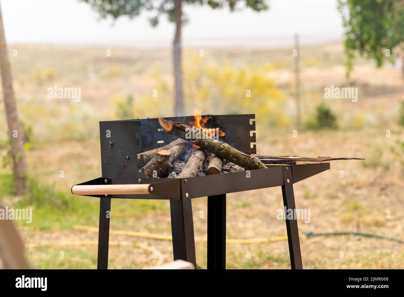 portable barbecue with burning wood prepared for grilling meat in the ...