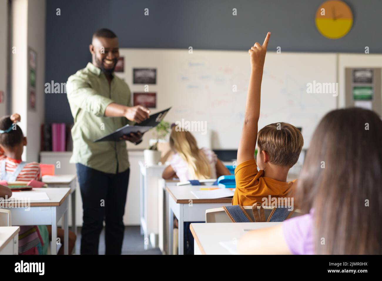 African american young male teacher pointing on caucasian elementary ...
