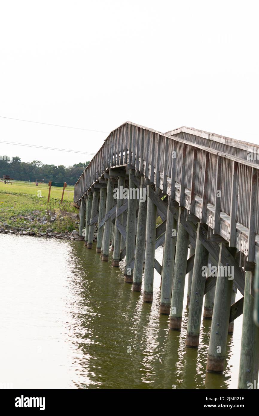 Short wooden bridge arching over shallow, murky water Stock Photo - Alamy