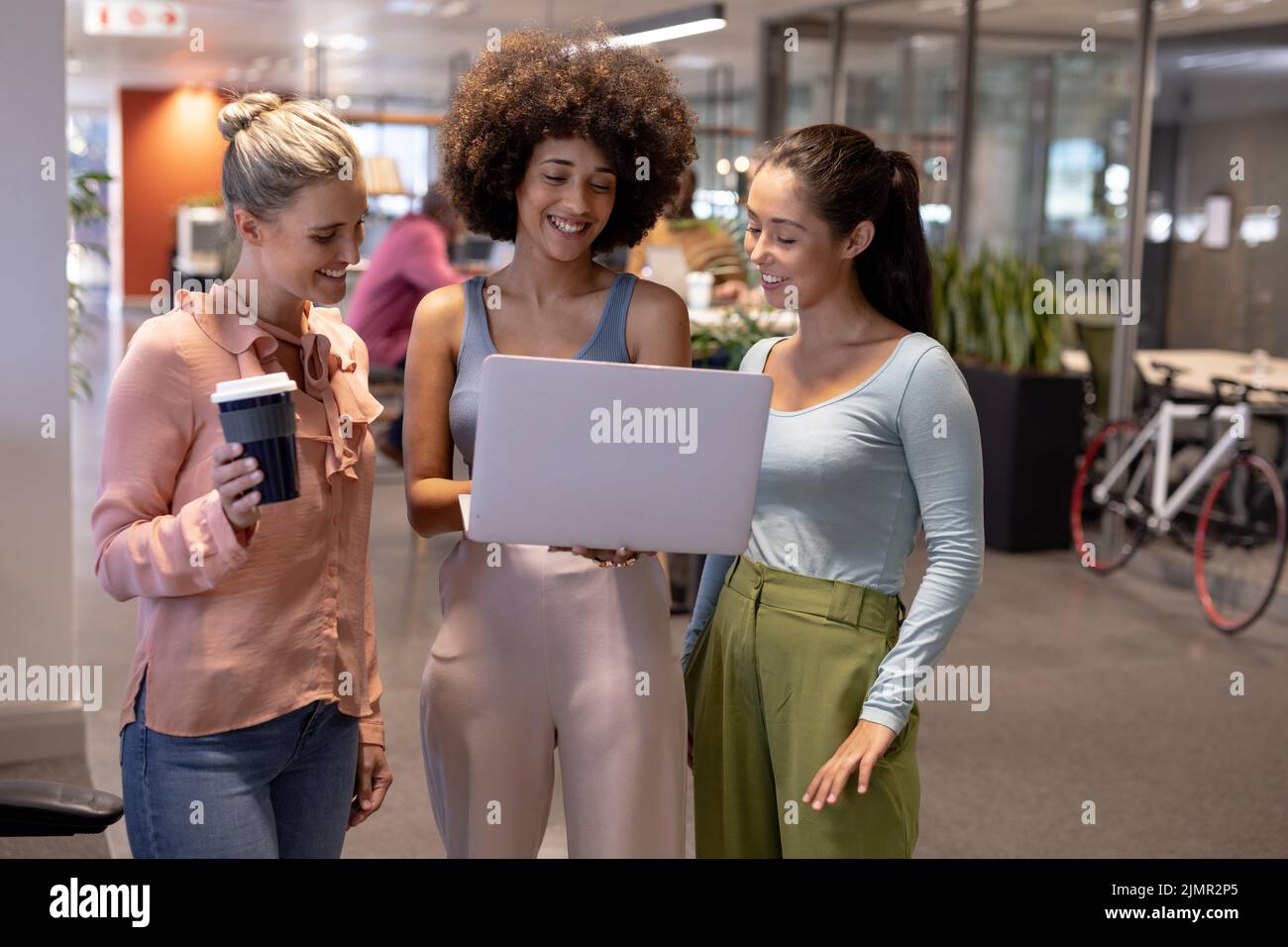 Happy multiracial female advisors discussing over laptop while working ...