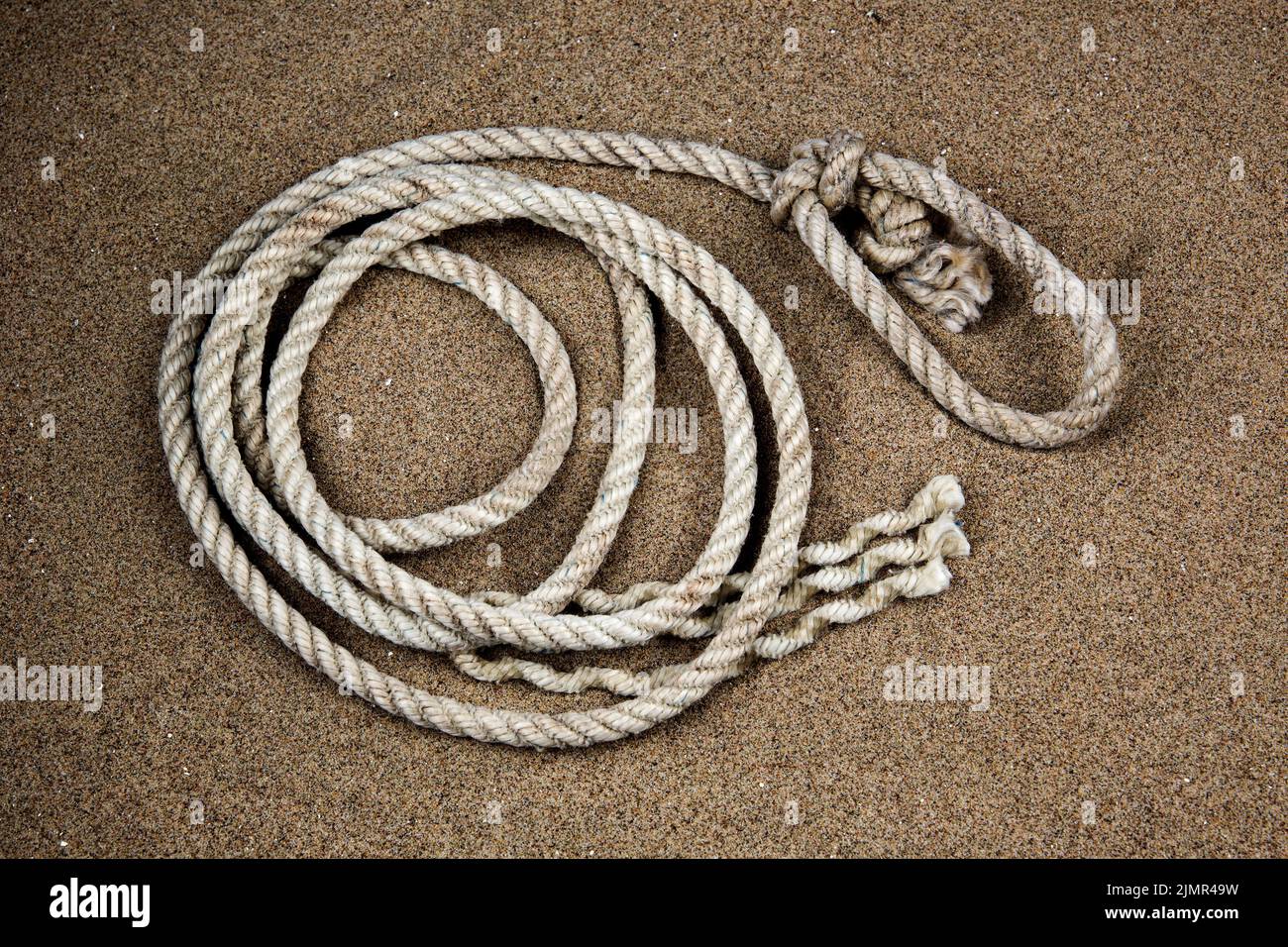 Old rope coil lying on a sandy coastal beach Stock Photo - Alamy