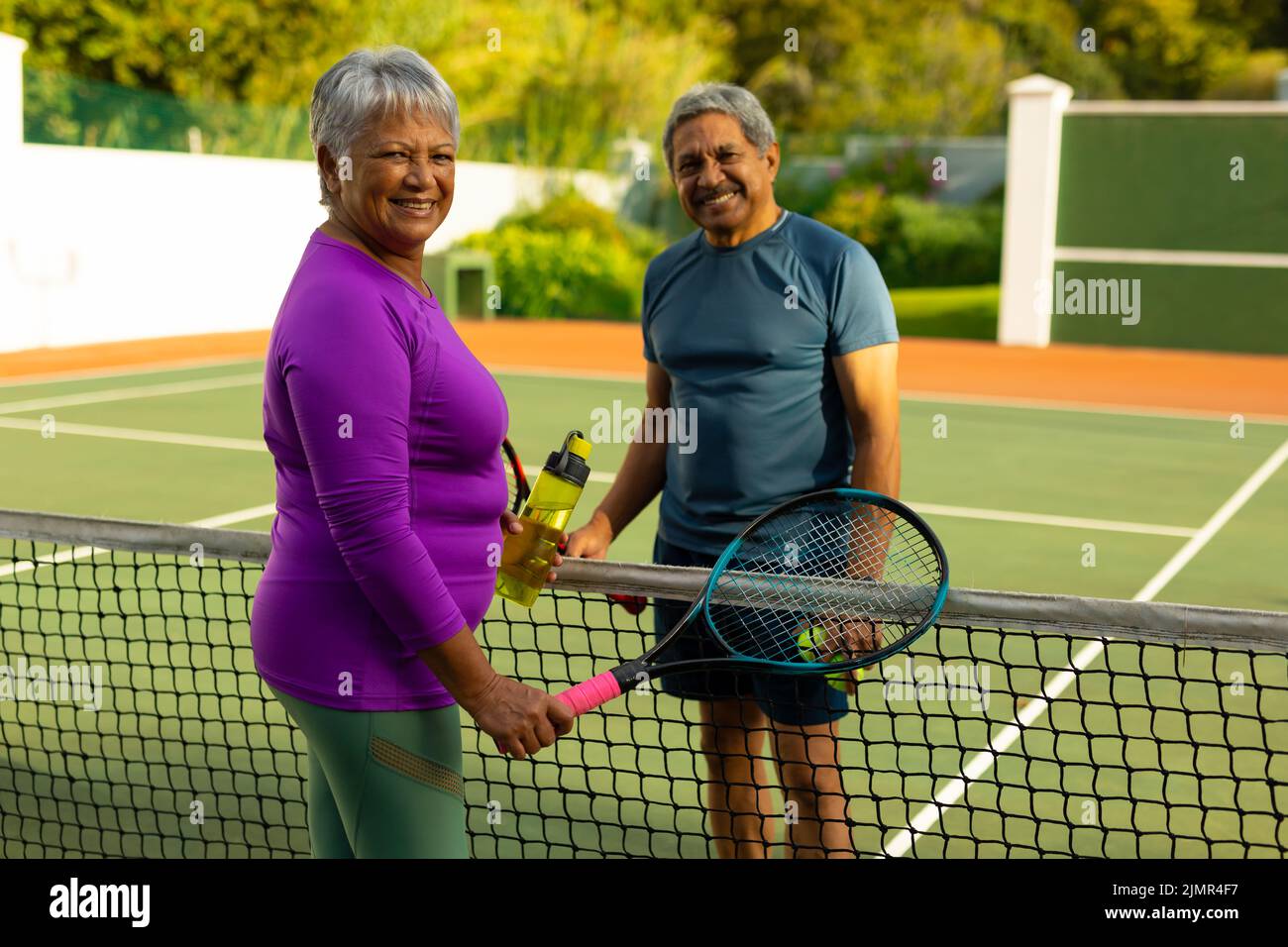 Portrait of smiling biracial senior man standing with wife holding ...