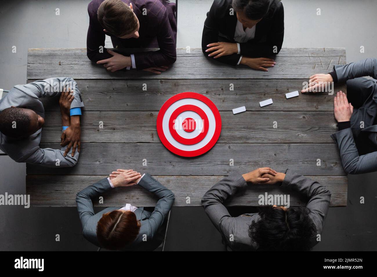 Team of business people pointing at red target at meeting table ...