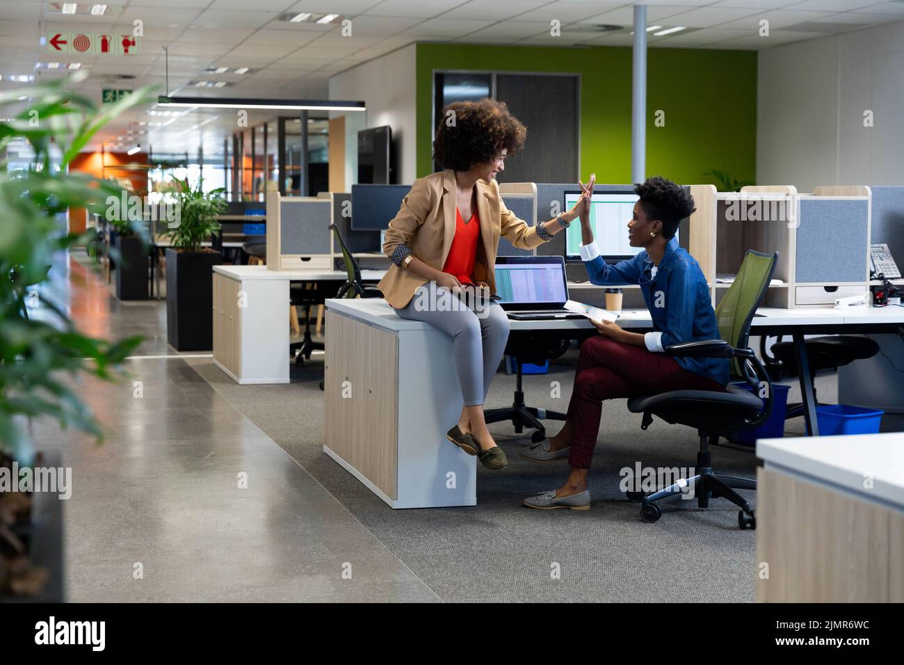 Happy biracial businesswomen giving high-five in meeting while sitting ...