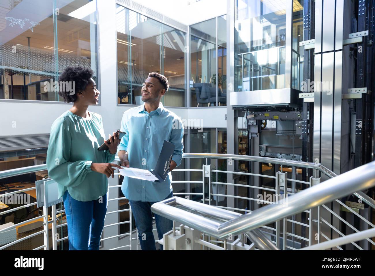 Happy african american professionals discussing over file at staircase ...