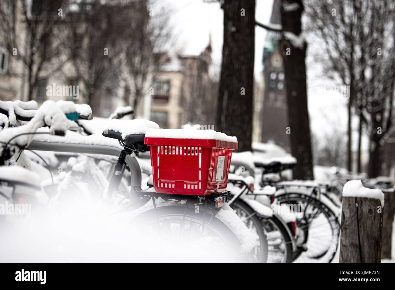 A red porter on a bike on the street after fresh snow has fallen onto ...