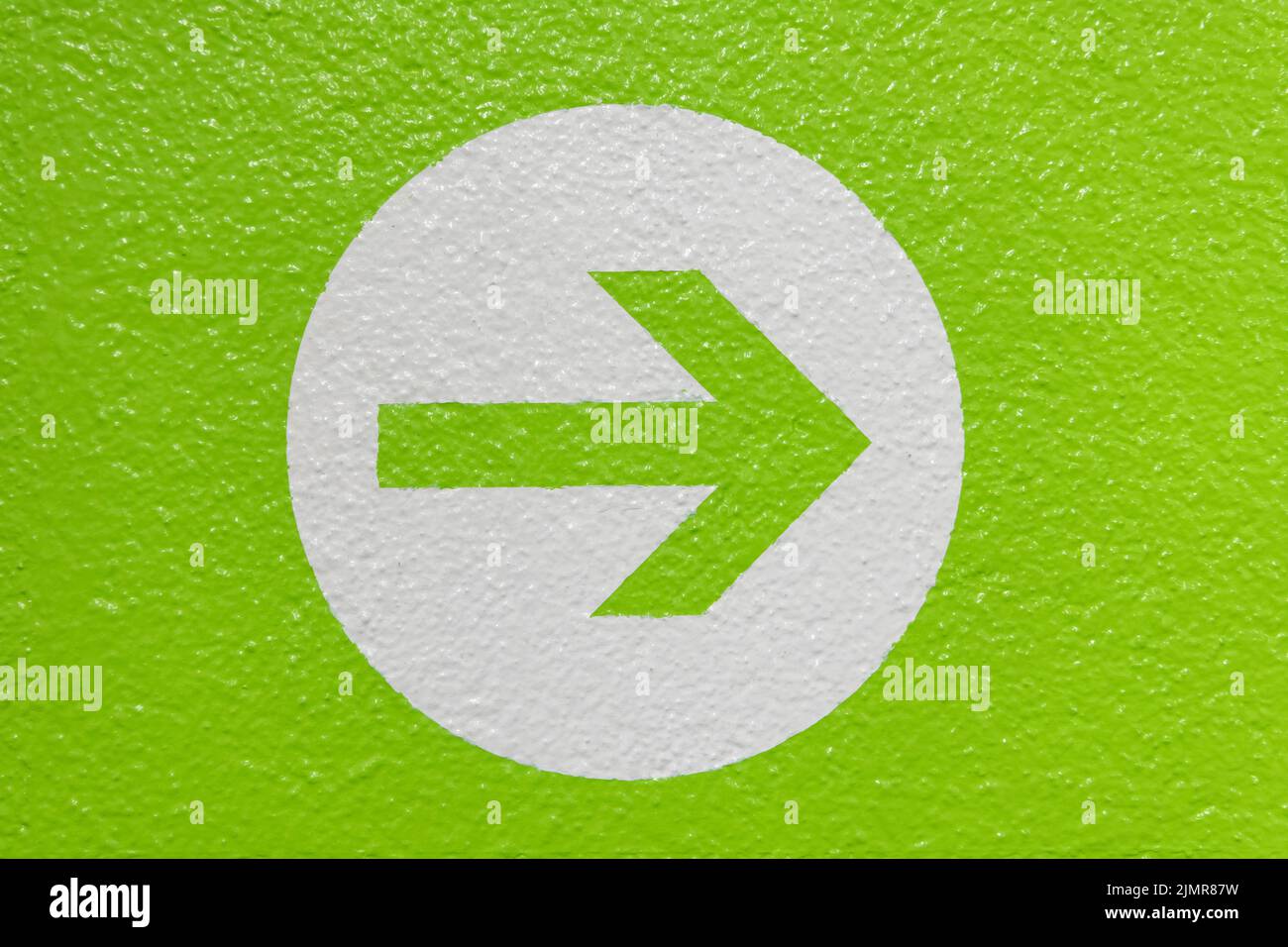 An arrow on a white circle isolated on a green wall showing the ...