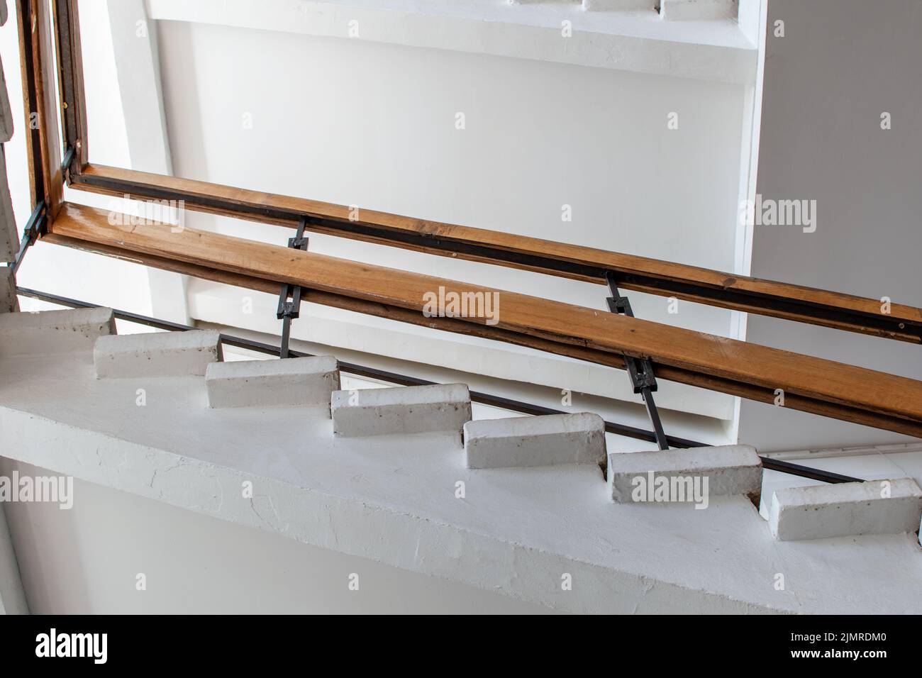 White stone staircase with wooden railing against a white ceiling ...