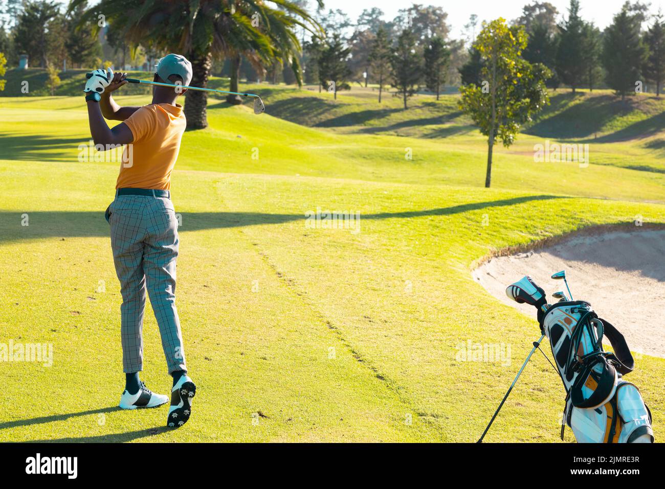 African american young man playing golf with golf club on grassy land ...