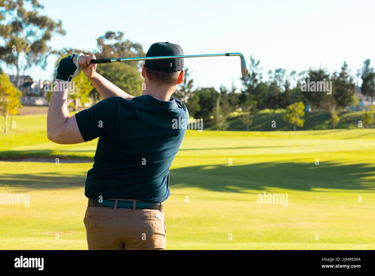 Rear view of caucasian young man playing golf with with golf club ...