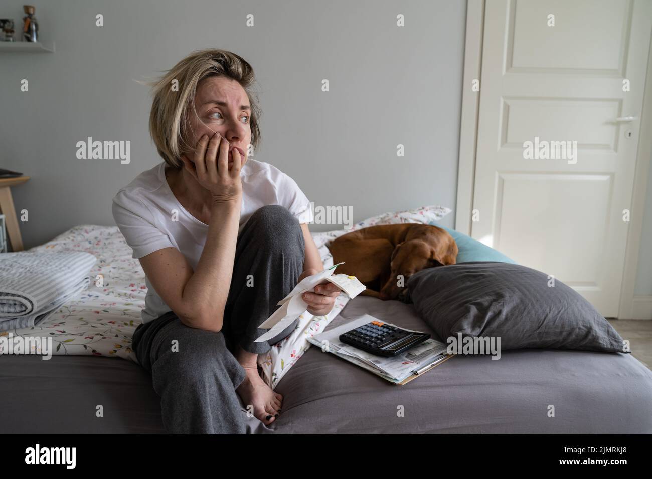 Unkempt mature woman looks away propping chin with hand to get ...