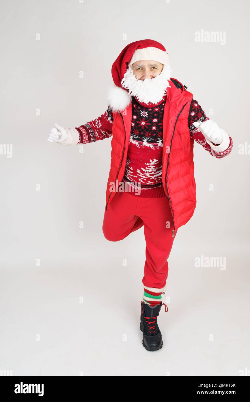 Christmas holidays concept. Cheerful Santa Claus dances on one leg ...