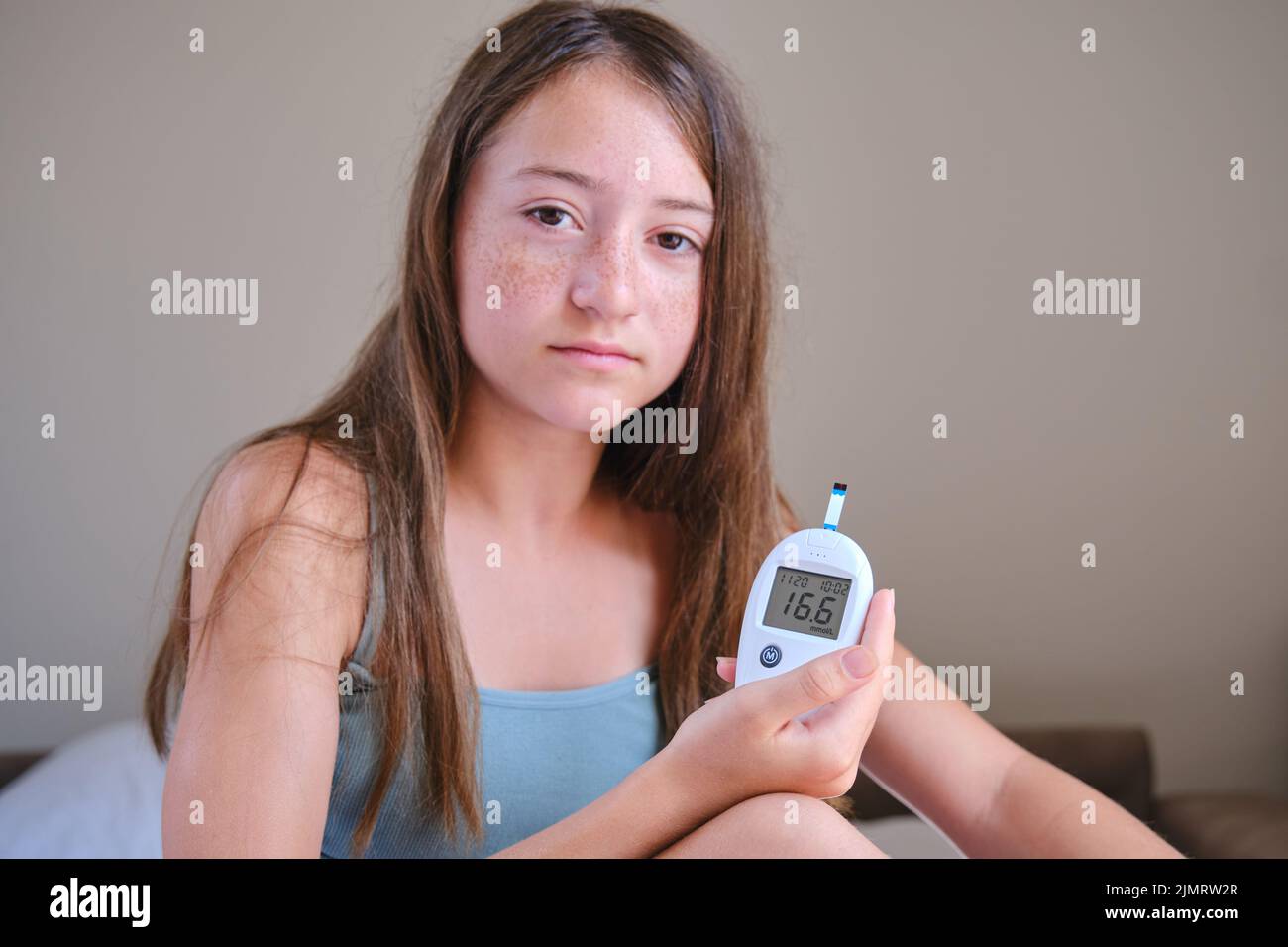 A teenage girl shows the screen of a glucometer with the results of a ...
