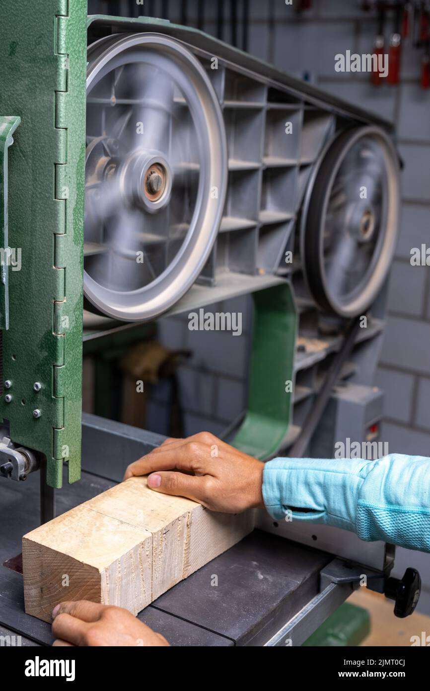 A vertical close-up of a woman carpenter cutting a block of wood with a ...