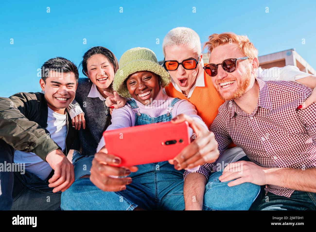Five young multiethnic friends taking a selfie together outdoors under ...