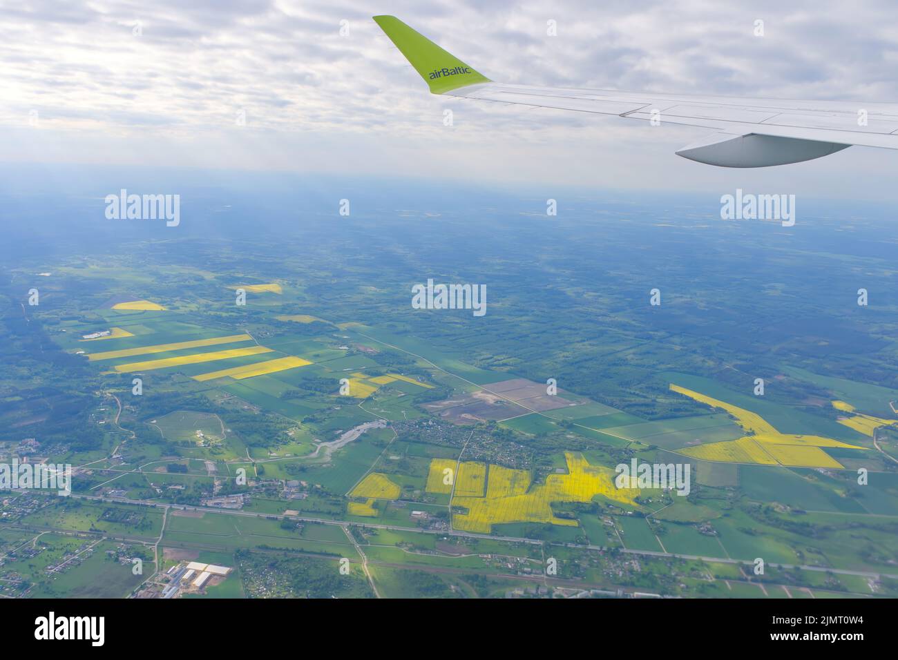 The wing of an airborne aircraft over land and water. sunny weather ...