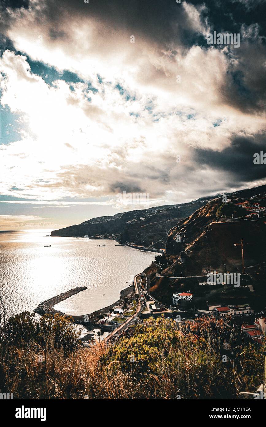 A vertical shot of cliffside buildings in Madeira Island by the ocean ...