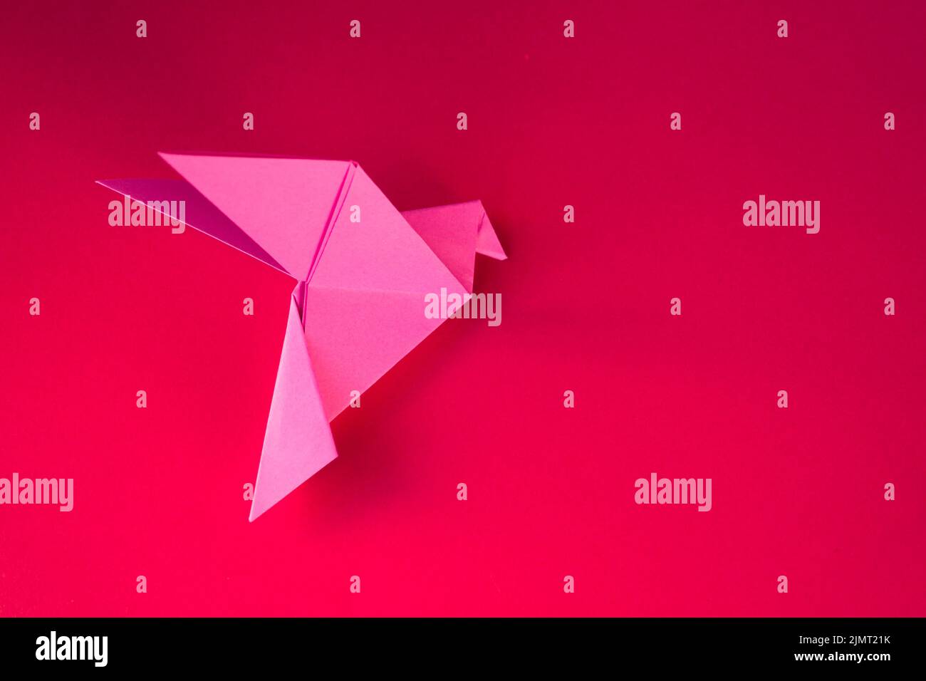 Pink paper dove origami isolated on a red background Stock Photo - Alamy