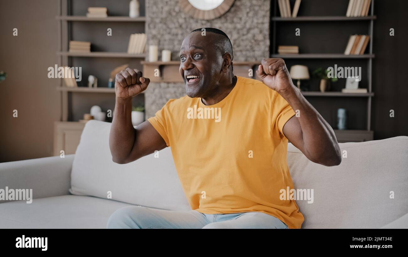 Senior football fan african american man bachelor sit on cozy sofa in ...