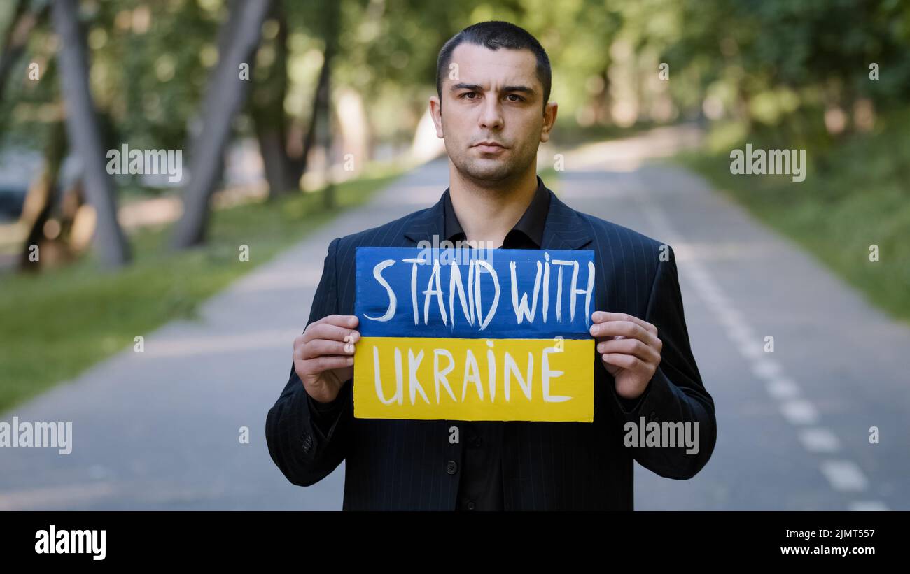 Portrait sad serious man activist patriot guy stand outdoors hold ...