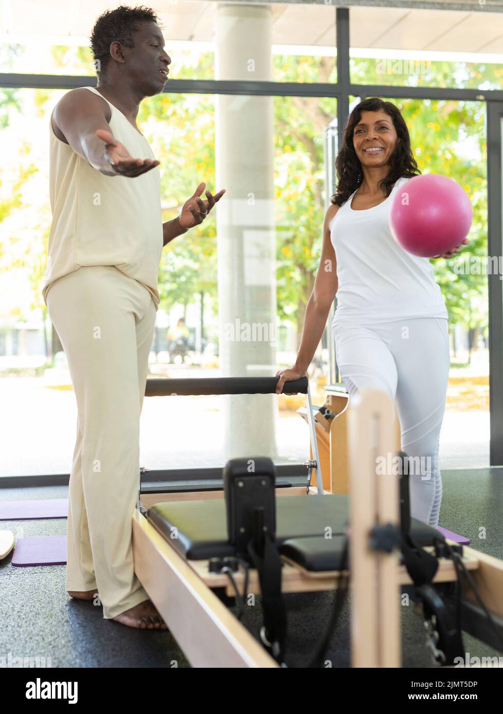 African american trainer teaches women to do pilates with pink balls ...