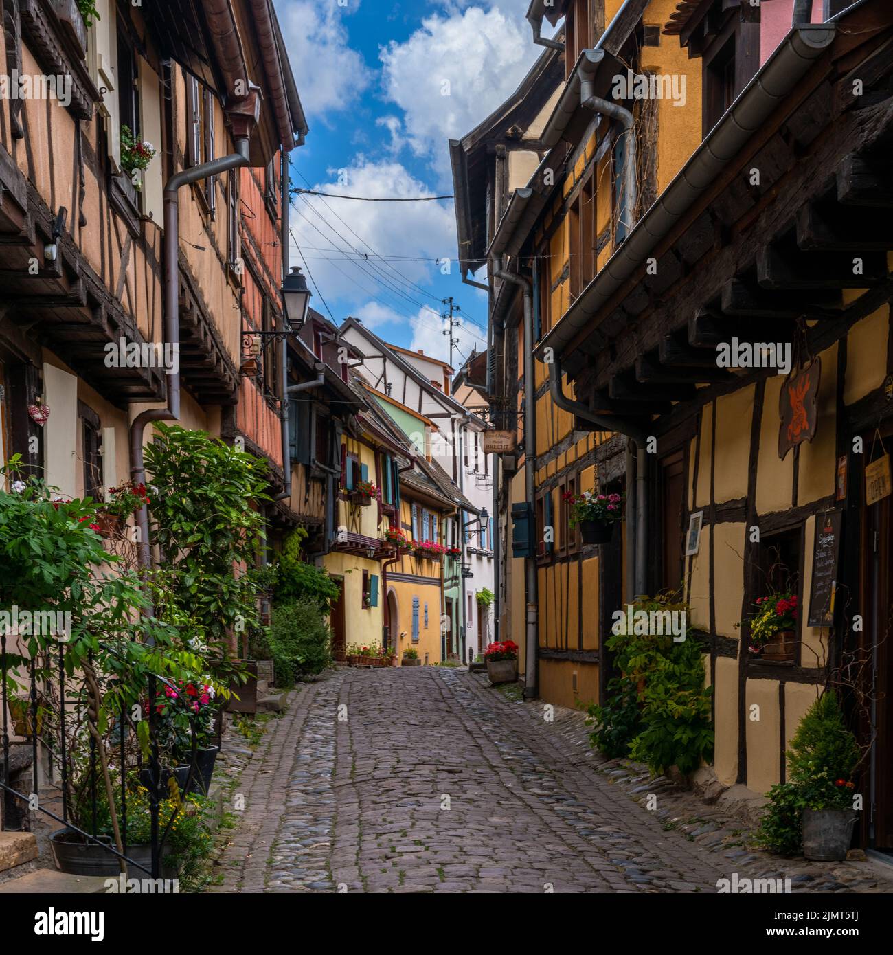 Narrow cobblestone street with colorful historic half-timbered houses ...