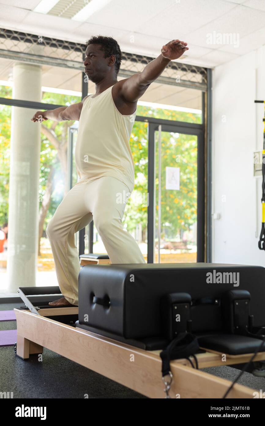 Man stretching on pilates reformer in gym Stock Photo - Alamy
