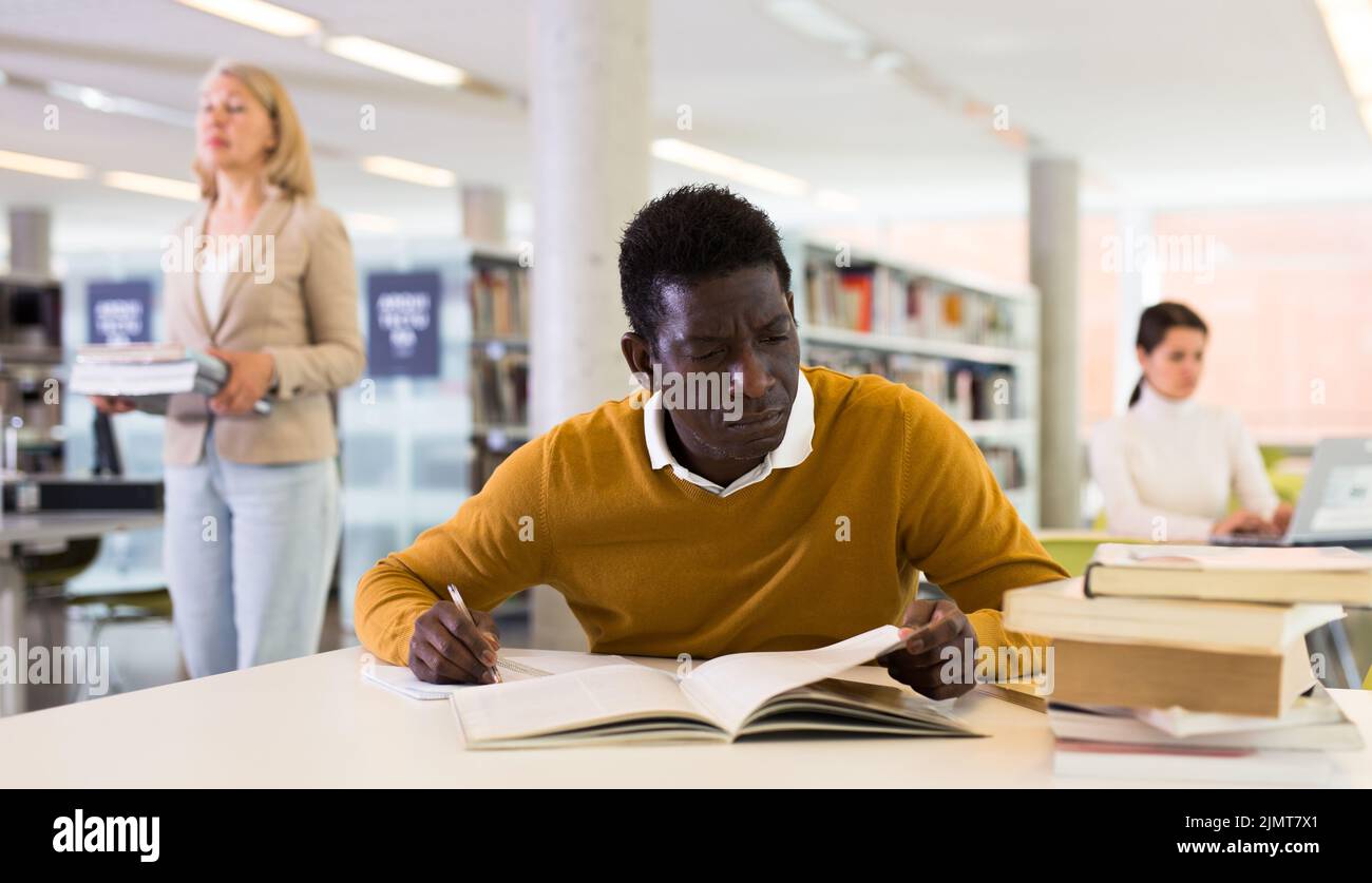 Intelligent african-american male student engaged in research working ...