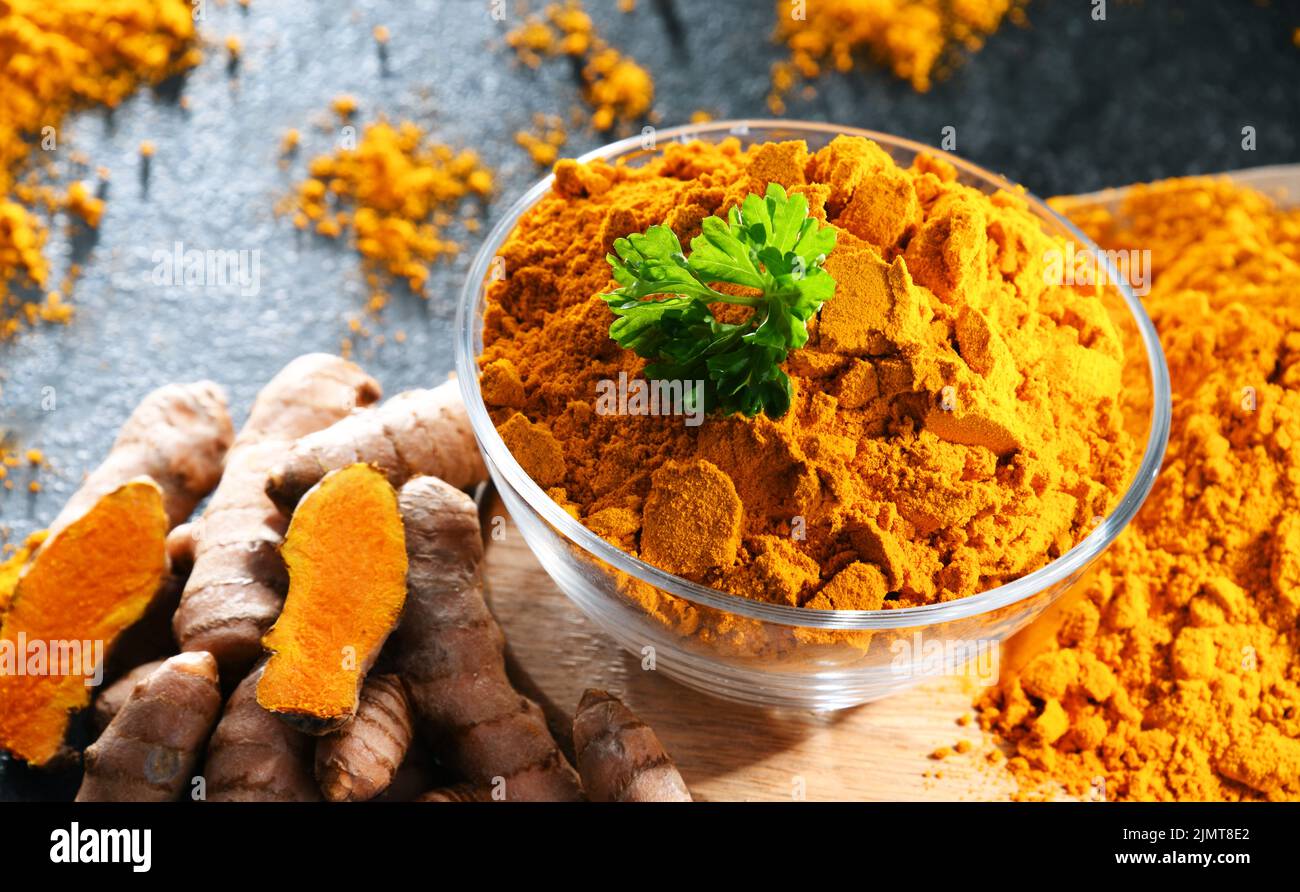 Composition with a bowl of ground turmeric and its fresh rhizome Stock ...
