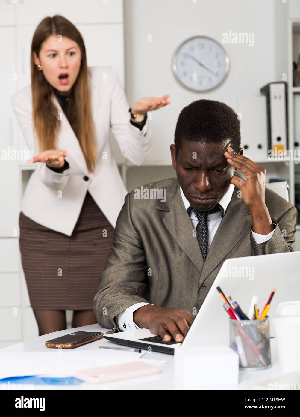 Angry woman boss pointinting to misses in work to man manager working ...